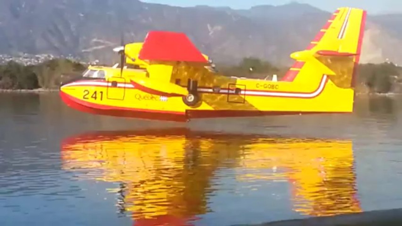 Un avion canadair remplie ses réservoirs d'eau sur un lac ...